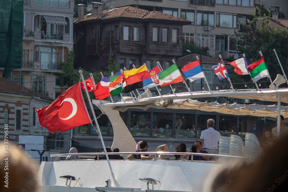 Flags of different countries and tourists traveling around the ship ...