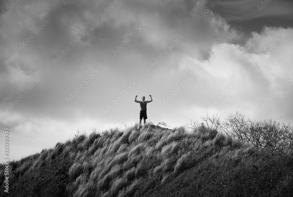 Strong man flexing on hill top. People power, strength and confidence ...