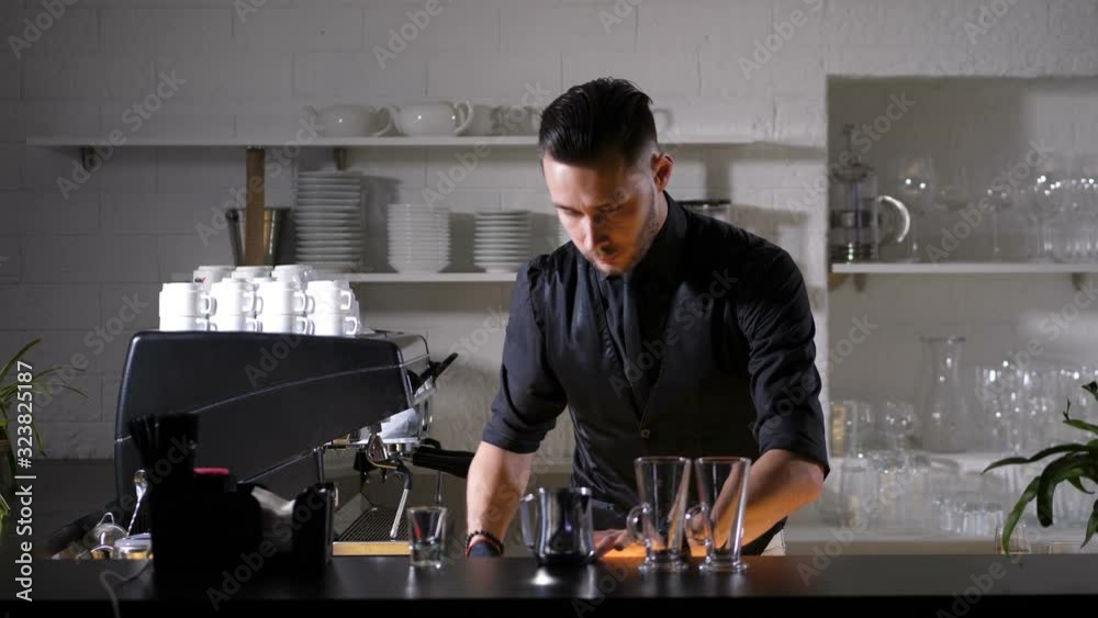 Professional male barista standing at bar counter doing trick with ...