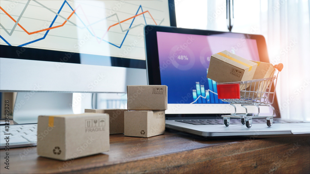 Online shopping, Boxes on table and in trolley on a laptop keyboard and ...