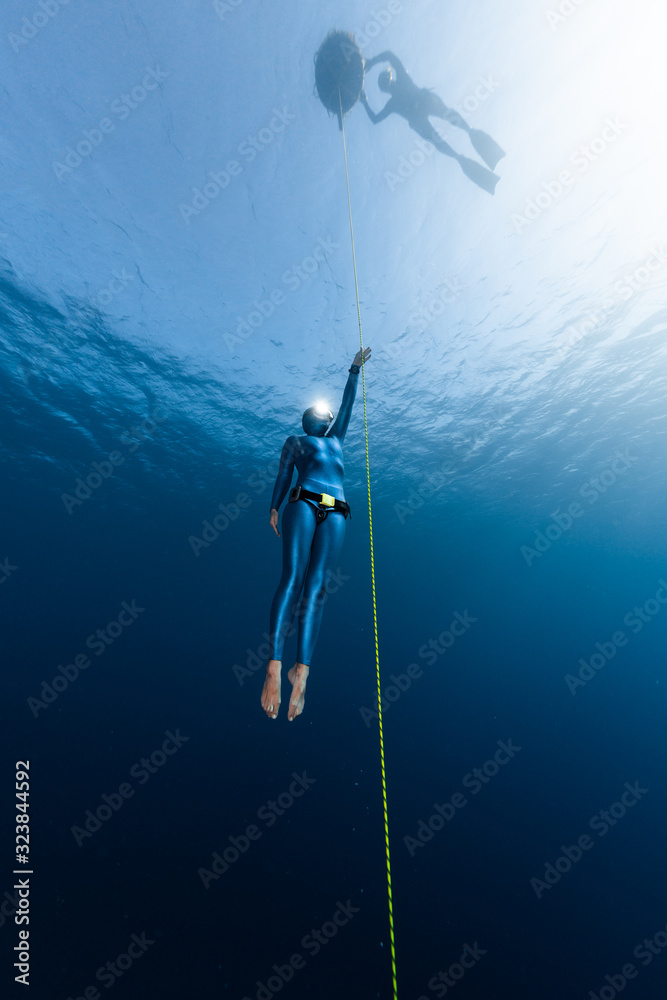 Freediver ascends along the rope from the depth while another freediver ...