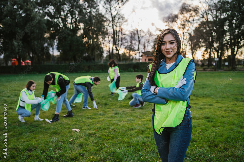 Group of friends at volunteer garbage collection event in a park ...