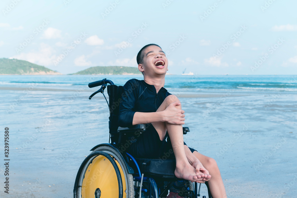 Asian special child on wheelchair is laugh happily on the beach ...
