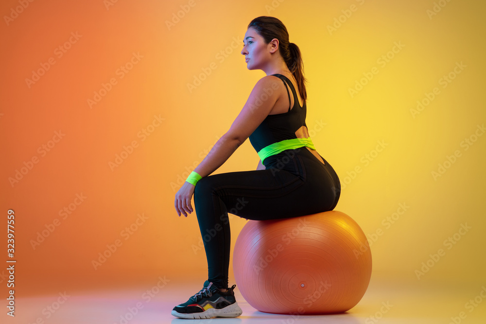 Young caucasian plus size female model's training on gradient orange ...
