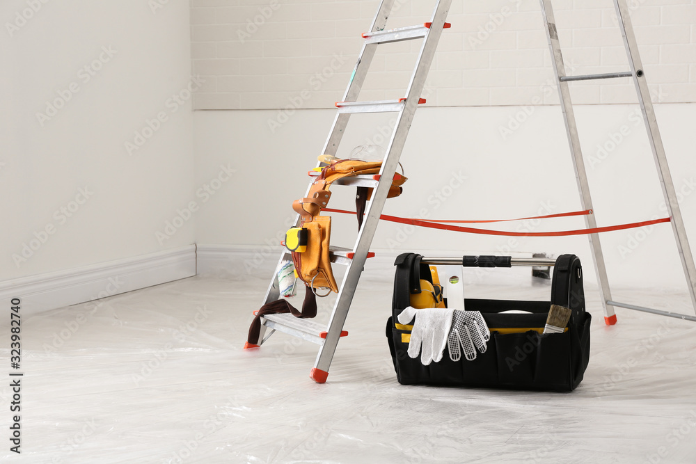 Stepladder and different tools near wall in room. Interior renovation ...