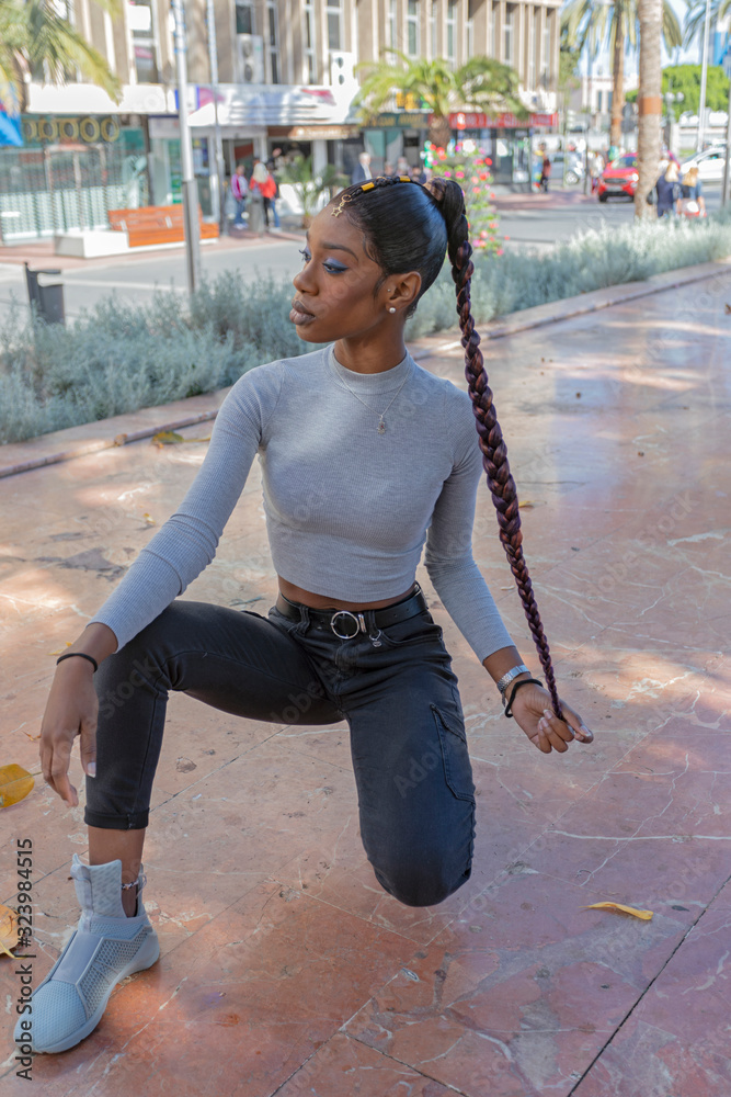 Beautiful african young girl touching the tip of her elaborate braid ...
