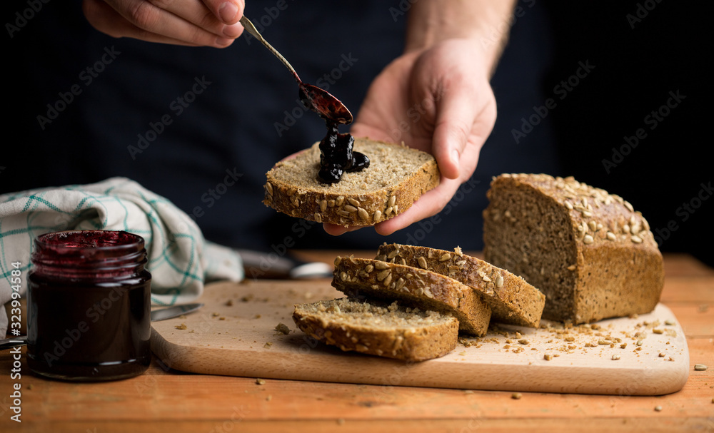 Person applying jam to fresh bread, visible moment of the jam flowing ...