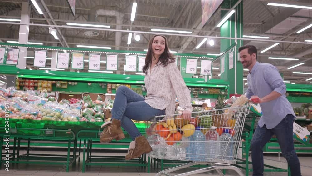 Young couple having fun while choosing food in the supermarket, man ...