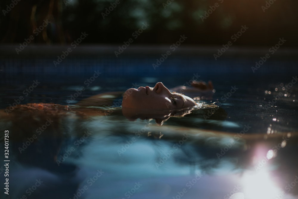 Side view of face above water surface of resting tranquil woman with ...