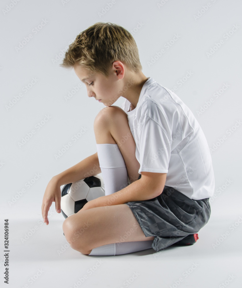 young boy sitting on the floor with soccer ball Stock Photo | Adobe Stock