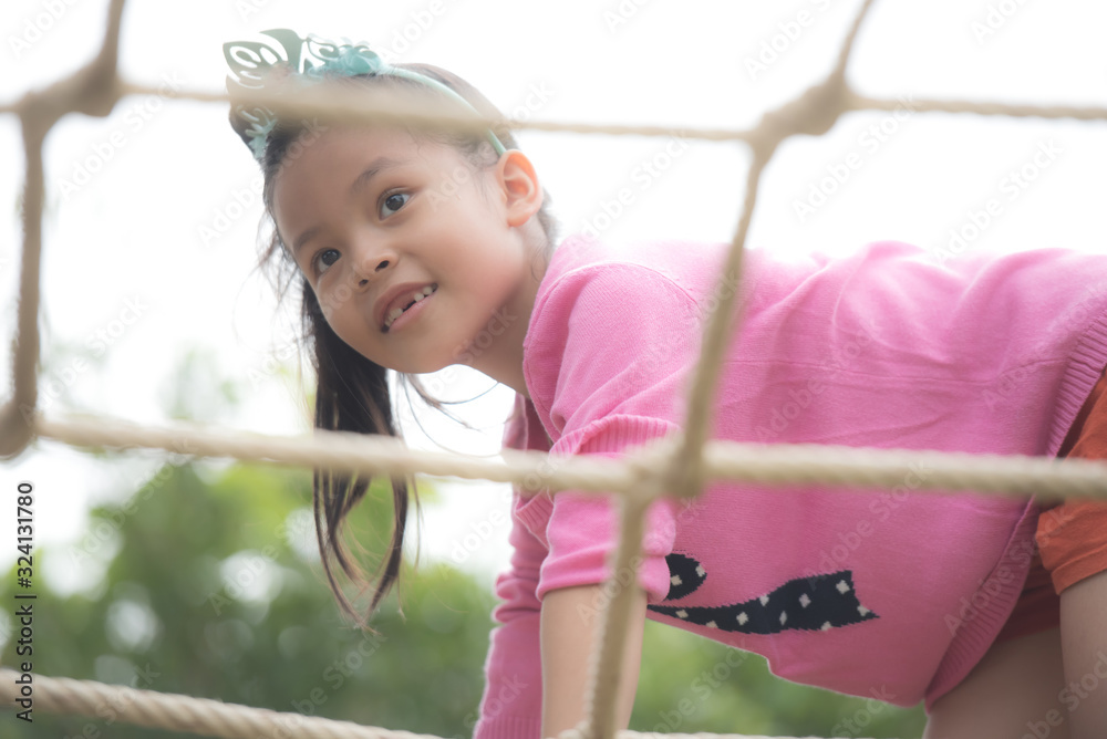 Little Girl with climbing gear climbing rope trail in an adventure park ...