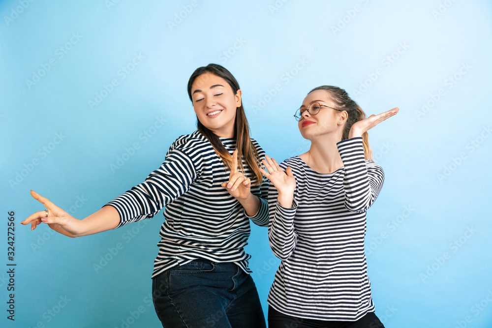 Dancing together. Young emotional women isolated on gradient blue ...