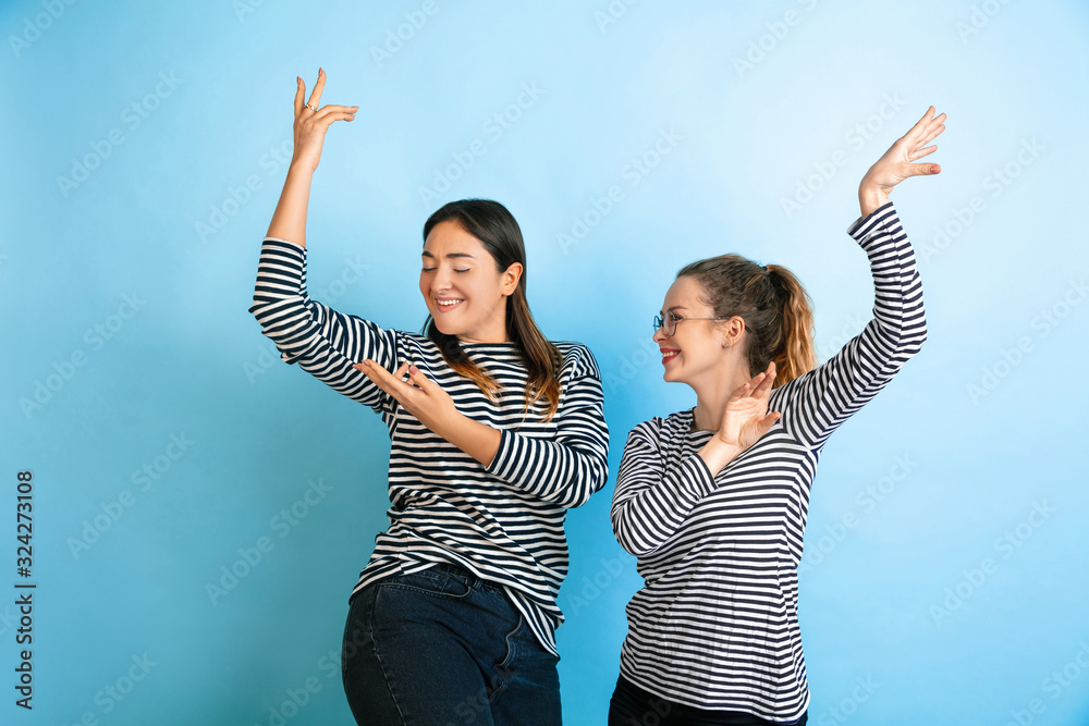 Dancing together. Young emotional women isolated on gradient blue ...