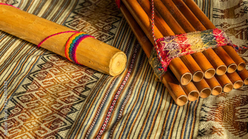 Andean instruments, Peruvian zampoña and rain stick on peruvian poncho ...