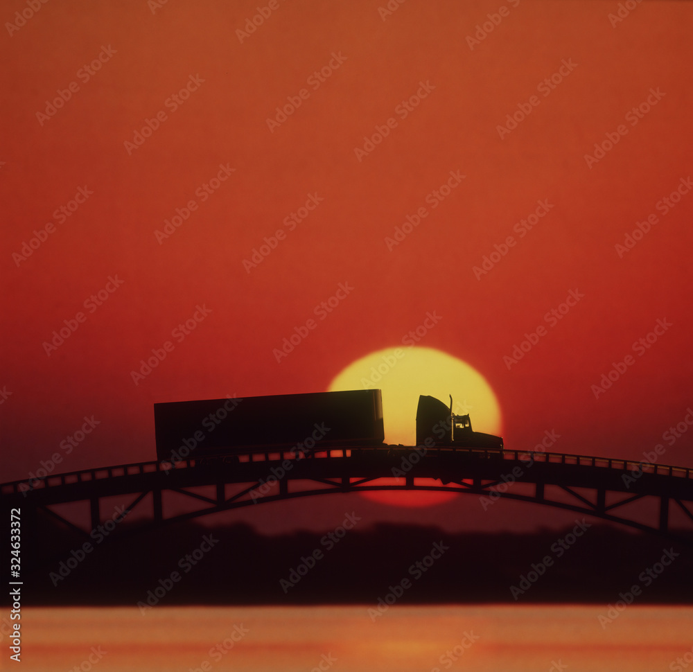 Semi Truck with trailer crossing bridge over water at sunset Stock ...