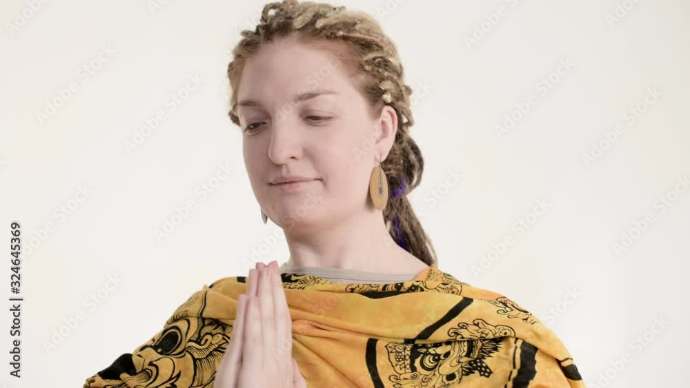 A girl with dreadlocks and hands in bracelets in a gesture of namaste ...