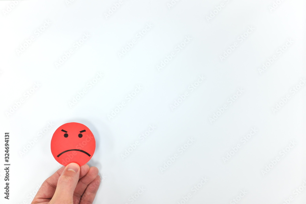 Hand holding a red angry face icon in white background with copy space ...