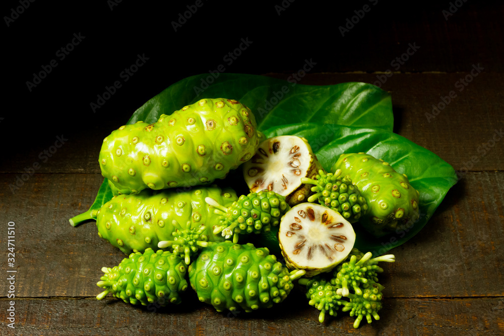 Pile of Noni fruit or Morinda Citrifolia and green leaf on wooden ...