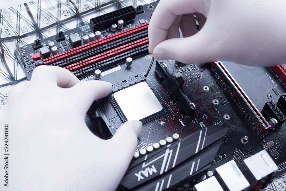 Hands of a technician assembling computer hardware parts new cpu is being mounted unto the ...