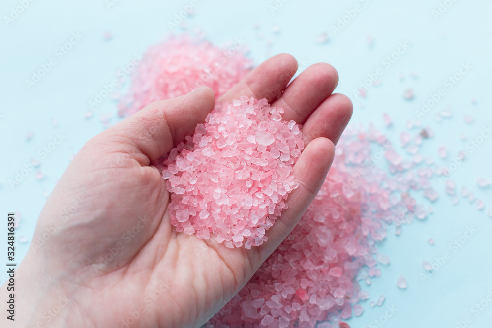 heap of crystals of pink sea salt with the smell of a rose on the palm ...