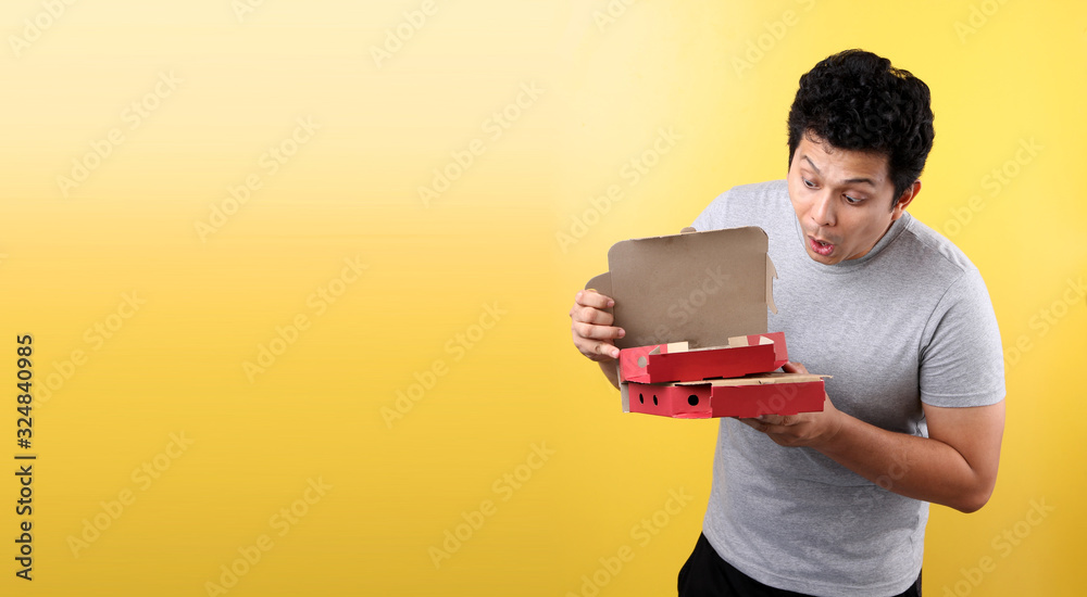 Young Asian man holding delivery box with Italian pizza scared in shock ...
