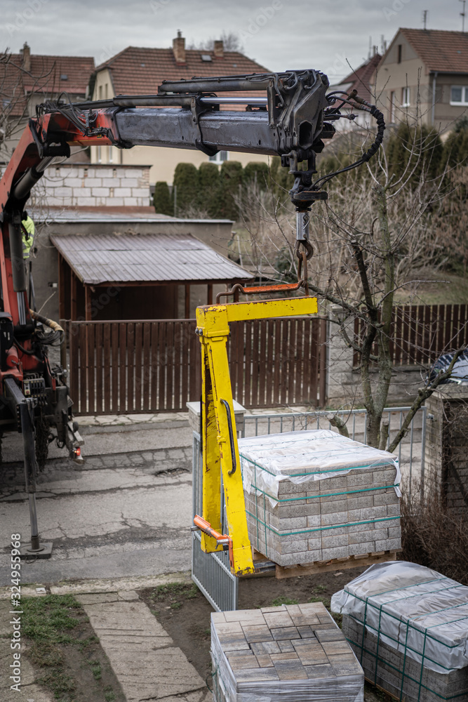 Hydraulic boom truck lifting a pallet with stacks of new concrete ...
