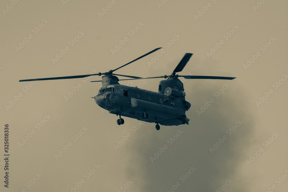 Military combat and war with Chinook helicopter flying through the ...