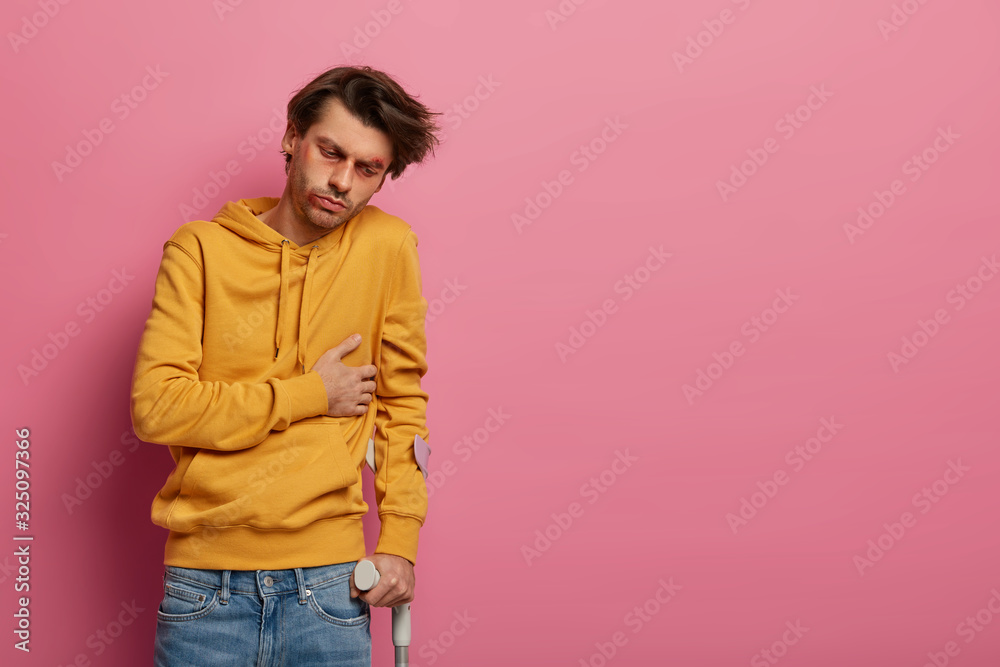 Photo & Art Print Upset male victim of accident walks with crutches ...