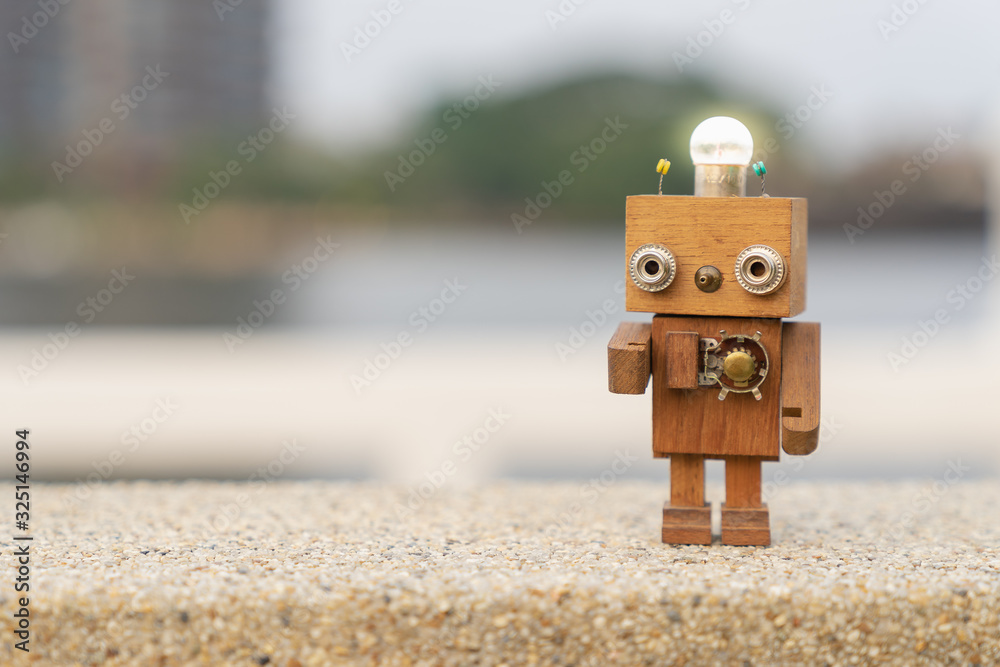Retro wood robot with light bulb on the head standing on the table with ...