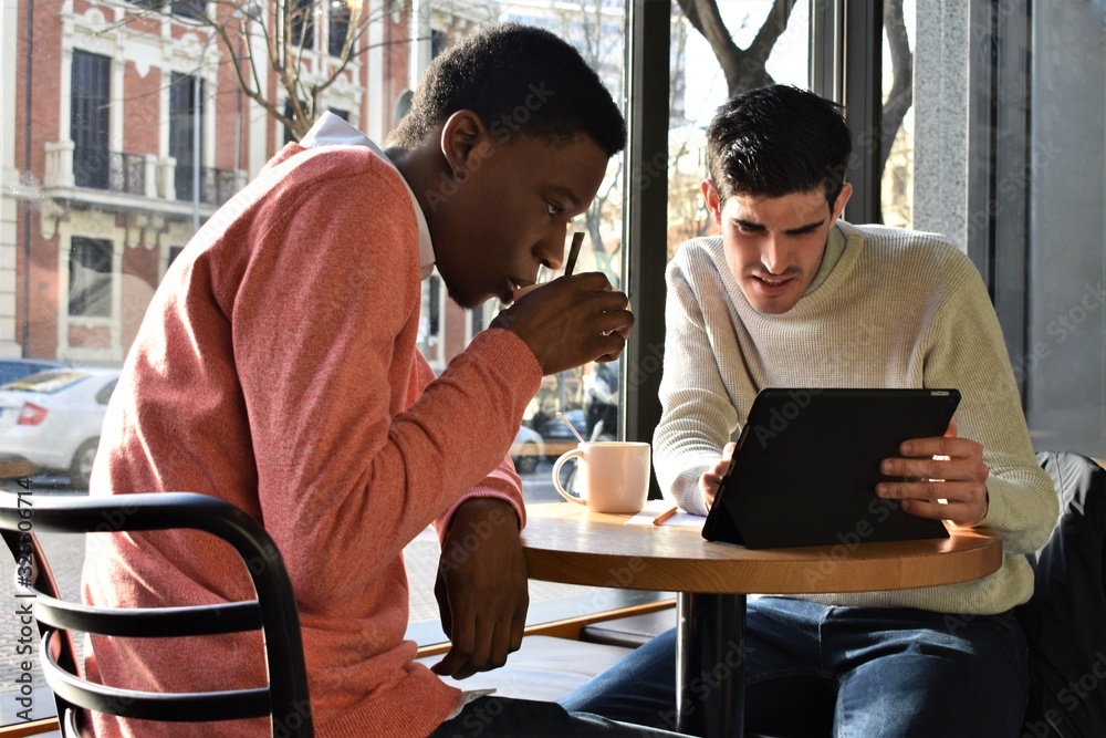 Side view of two young people of different ethnicity working together ...
