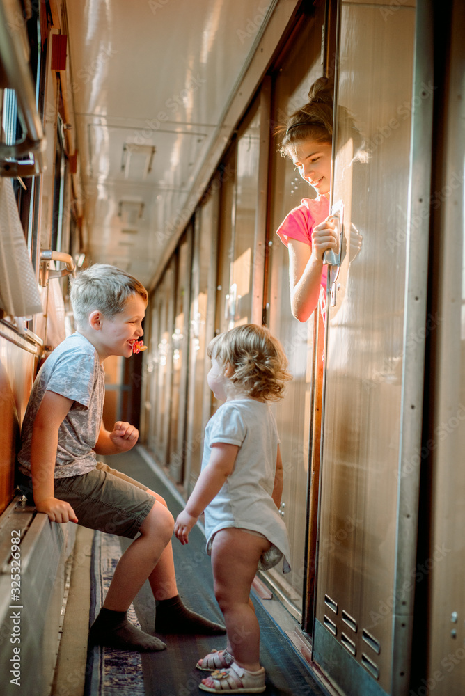 Three children play a train, family travel. two girls blondes younger ...