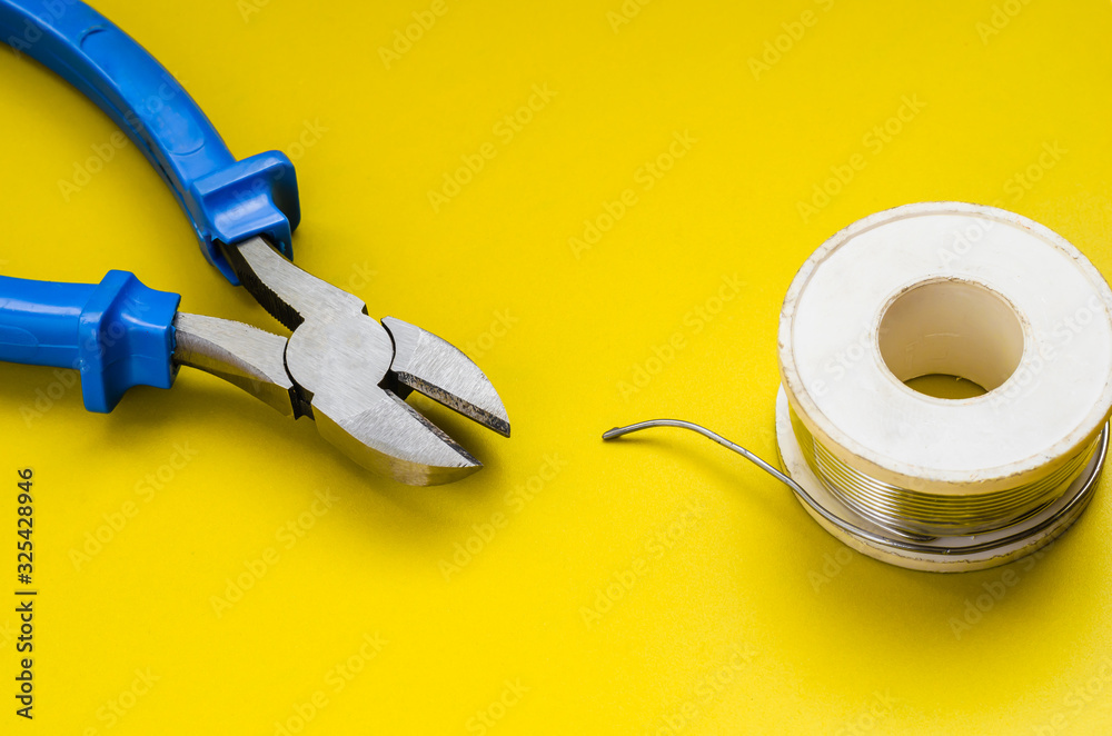Diagonal cutting nippers and solder on a yellow background. Nippers ...