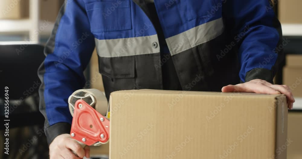 Close up of hands of Caucasian postal male worker in uniform packing ...