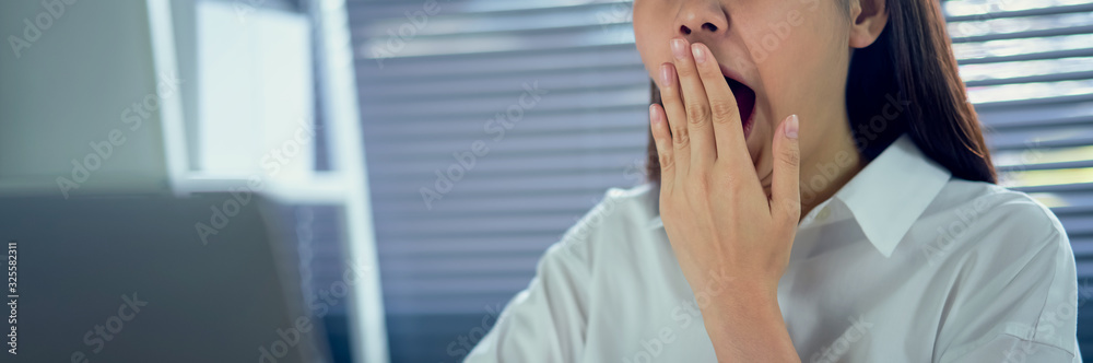 Asian woman yawning covering open mouth and showing a sleepy gesture ...