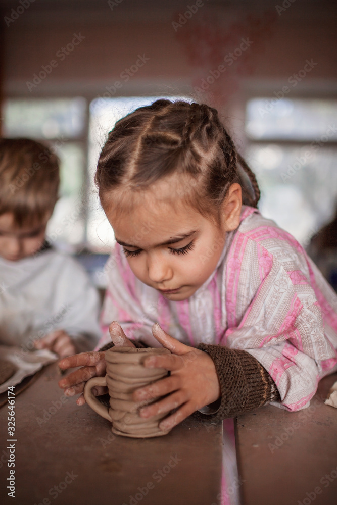 Cute little kids playing together with modeling clay in pottery ...