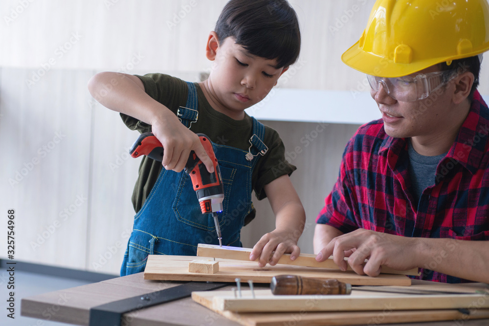Asian father teaching little boy to use the mechanic tools in workshop ...