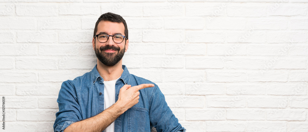 Handsome man with beard over white brick wall pointing finger to the ...