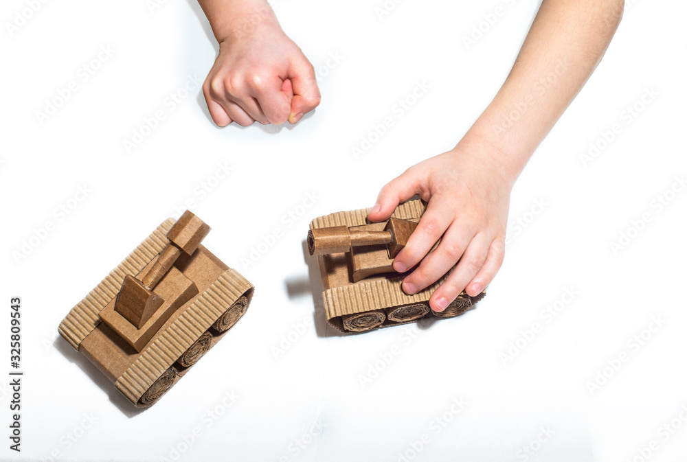 children's hands play with tanks. two toy tanks made by children from ...