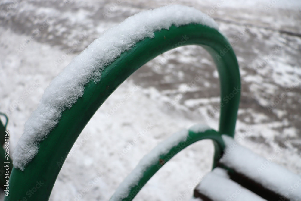Curved bench rail with snow on it. Handrail of the bench and rented ...