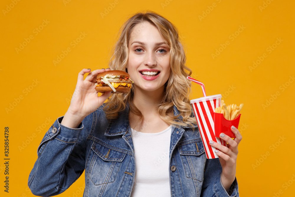 Smiling young woman in denim clothes isolated on orange background ...