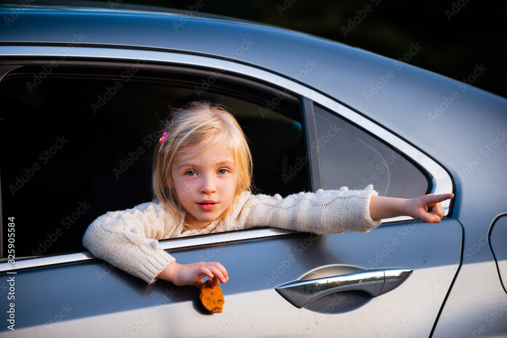 Little girl looks out the window in the car and something shows a hand ...