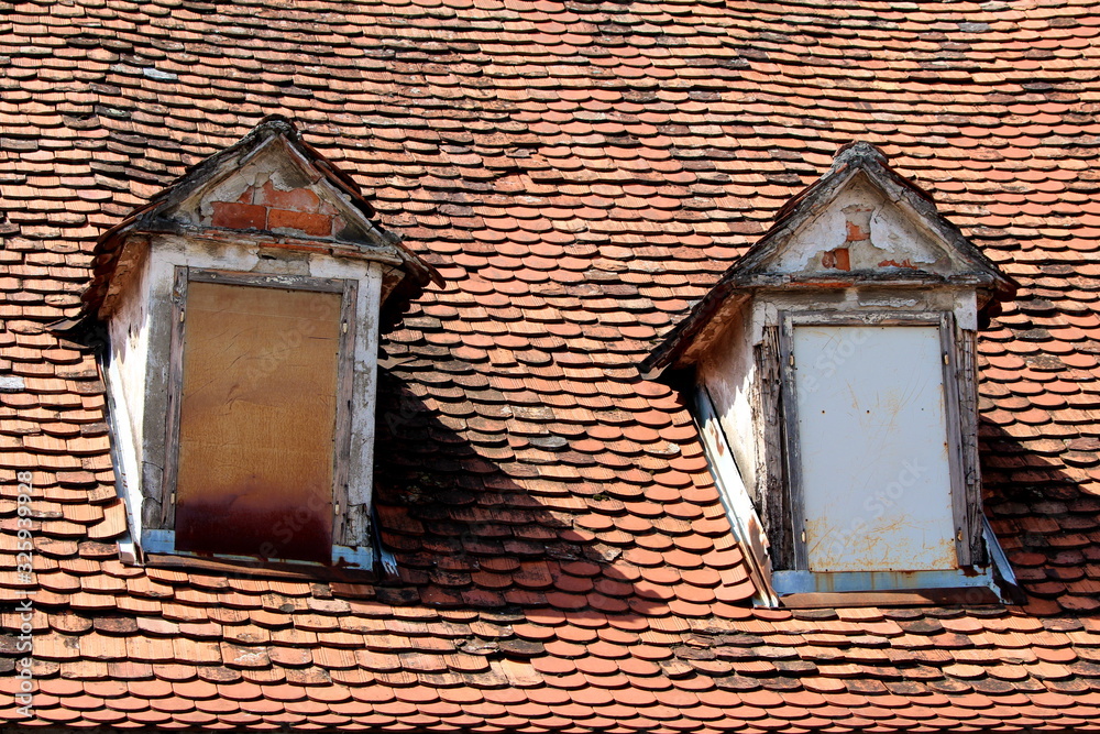 Front view of two old style roof windows closed with wooden boards ...