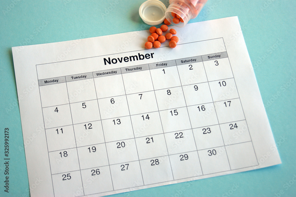 Inverted jar with orange pills and a calendar with marked dates on a ...