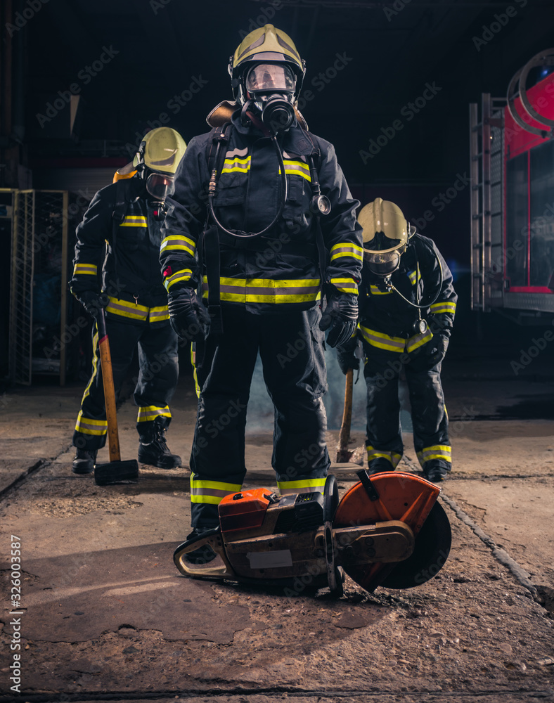 Group of three young fireman posing inside the fire department with ...