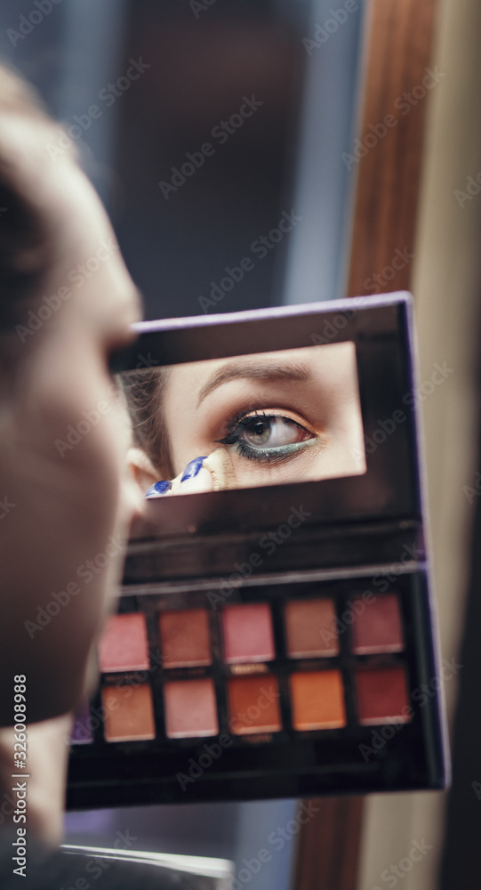 reflection of a female eye in a palette mirror with multi-colored ...