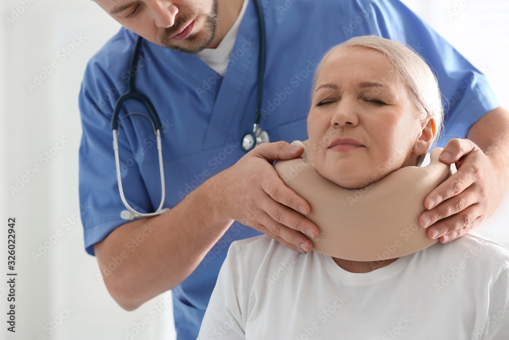 Orthopedist applying cervical collar onto patient's neck in clinic ...