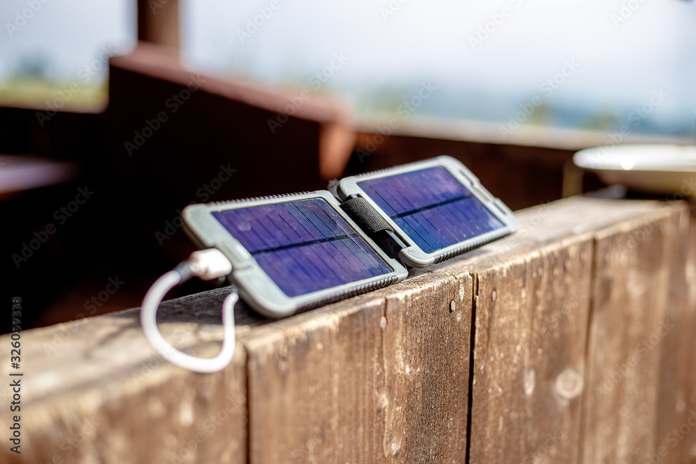 Portable solar panel charges the battery of a powerbank. Stock Photo ...