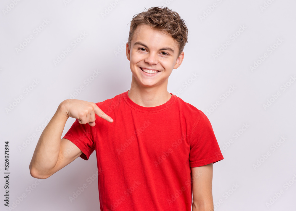 Portrait of handsome teen boy pointing oneself, on grey background ...