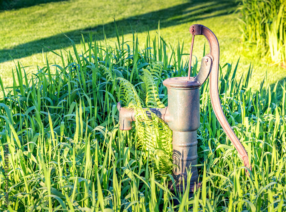 Old rusty water standpipe standing in in the high grass in the Swedish ...