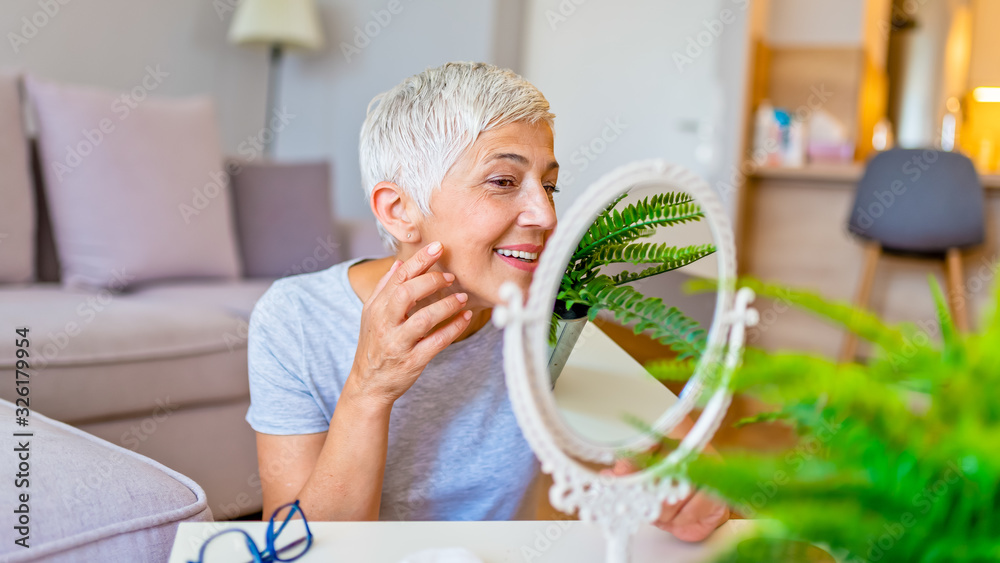 Foto de Senior female looking at sagging skin face in mirror, old age ...